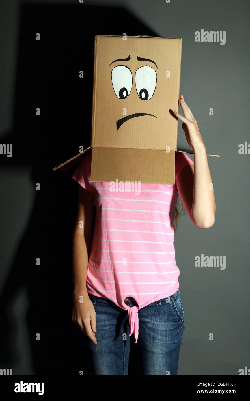Woman with cardboard box on her head with sad face, on grey background ...