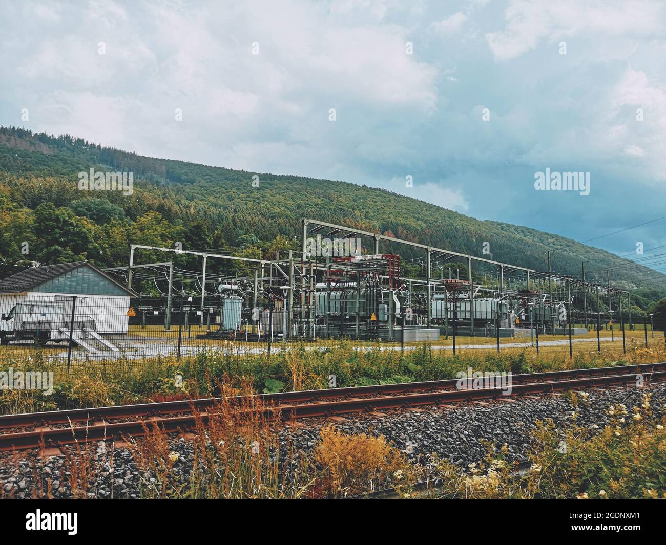 a train on a train track and electricity power plant with a mountain in ...