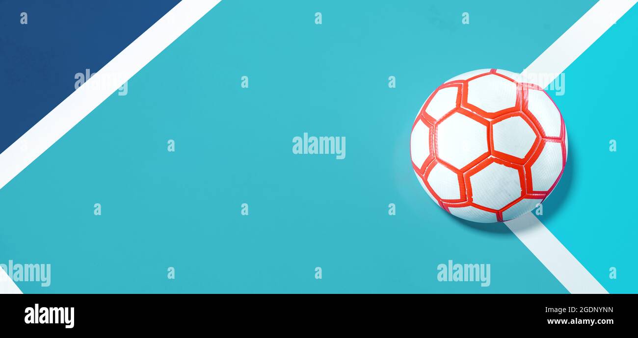 Close-up of a white orange futsal ball in the corner of a bright blue ...