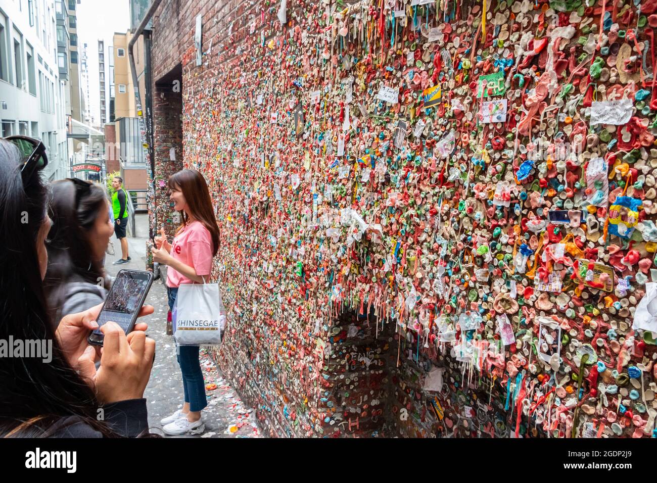 Tourists photograph the Seattle chewing gum wall tourist attraction ...