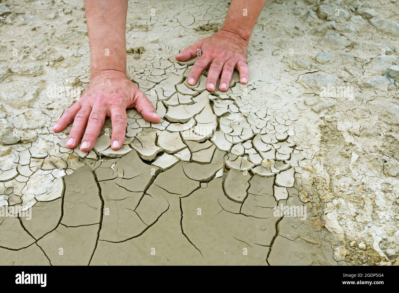 A man desperately seeking water during drought. Hands on dried soil ...