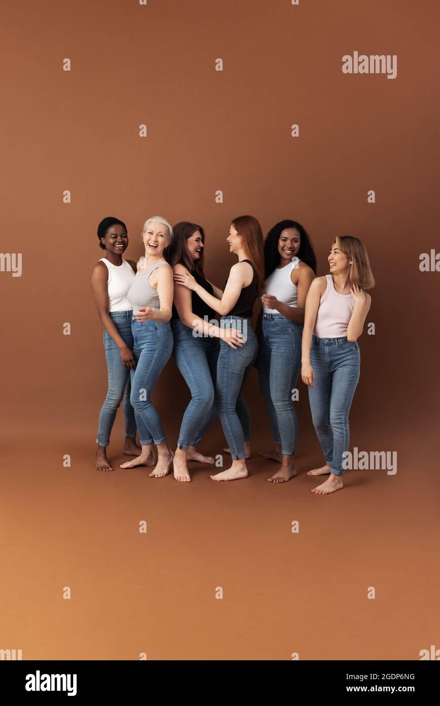 Six laughing women in casual dancing and having fun against brown ...