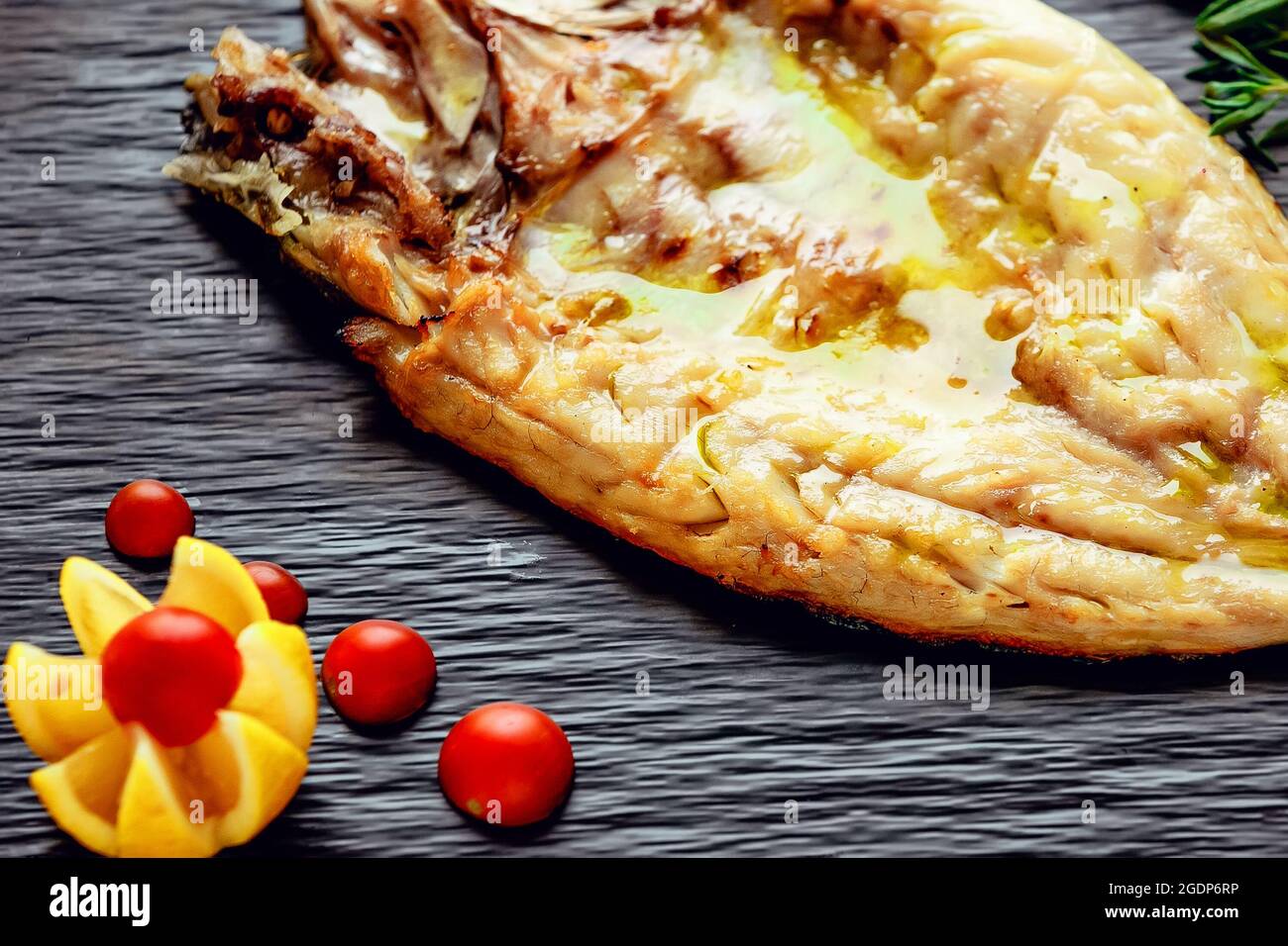 Grilled white fish served on a square stone plate Stock Photo - Alamy