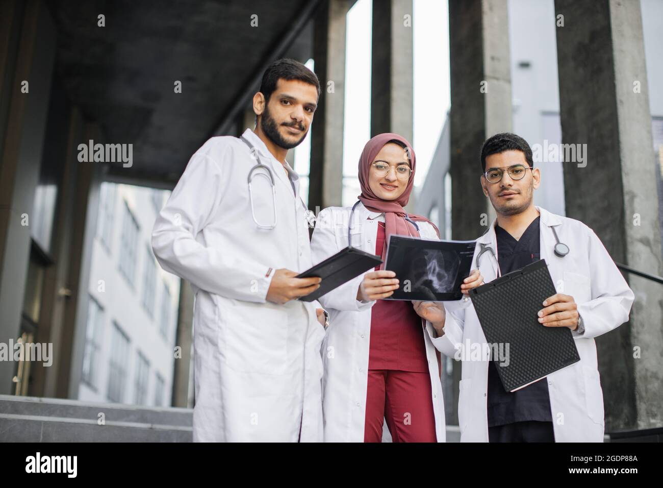 Tean of three Indonesian Malay doctors wearing white coats and scrubs ...
