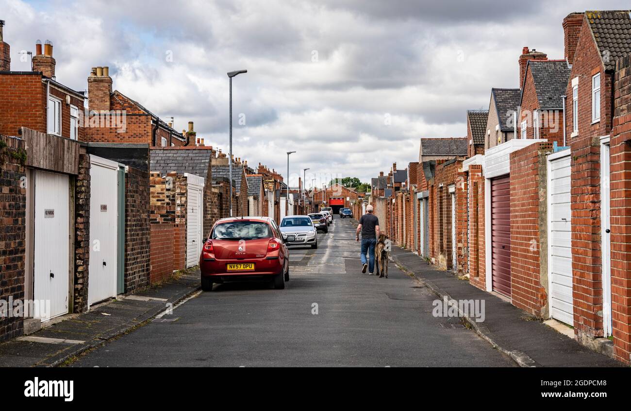 A man walks a dog up a back street of terraced housing in Ashington ...