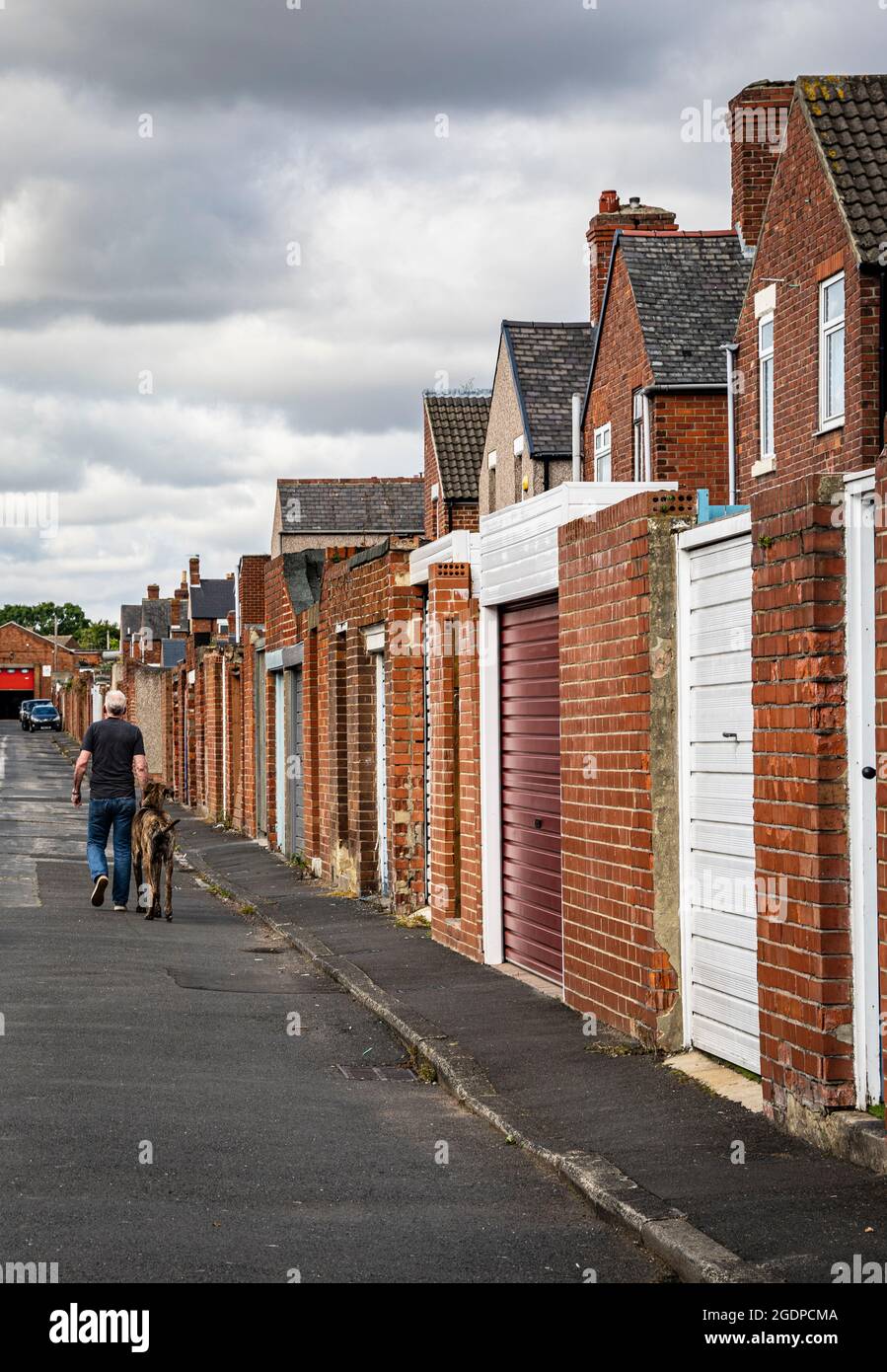 A man walks a dog up a back street of terraced housing in Ashington ...