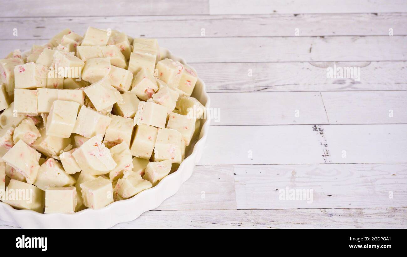 Step by step. Candy cane fudge cut in small cubes on a white serving ...