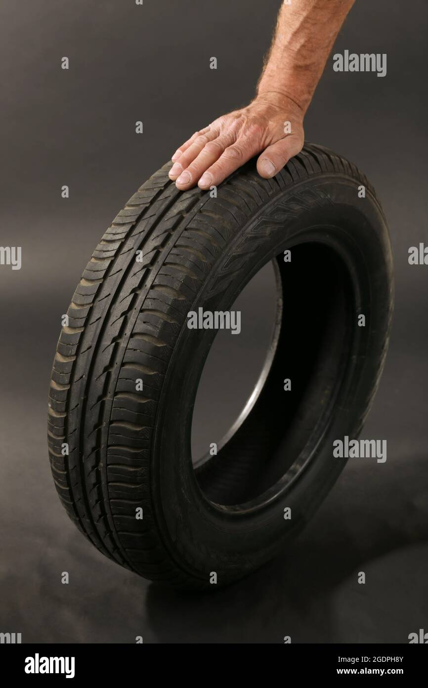 Man's hand holding tyre on dark background Stock Photo - Alamy