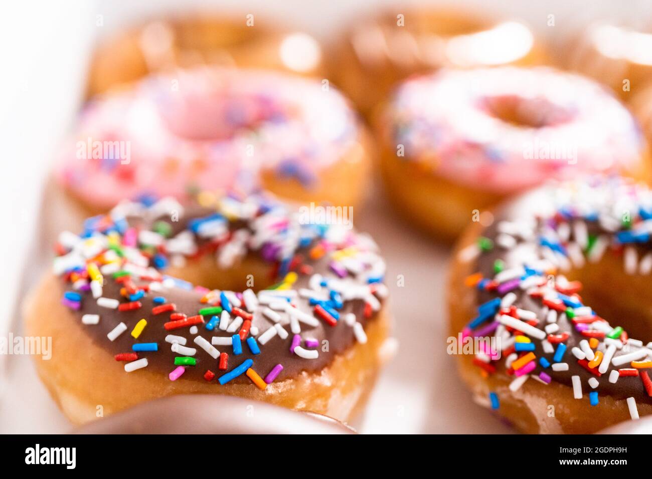 Variety of store-bought doughnuts in a white paper box Stock Photo - Alamy