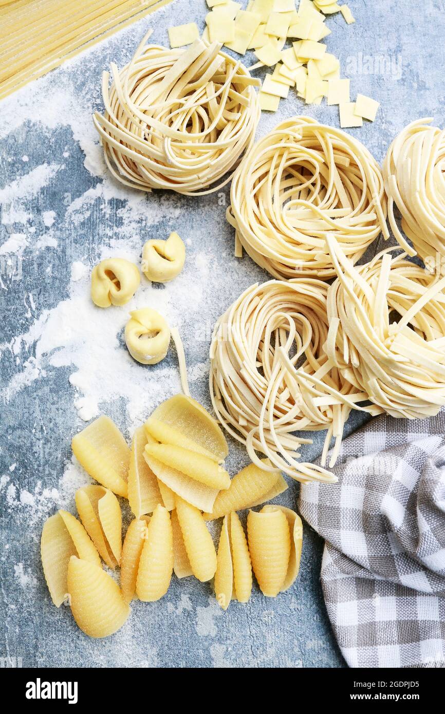Mixed types and shapes of italian pasta on grey stone, background. Copy ...