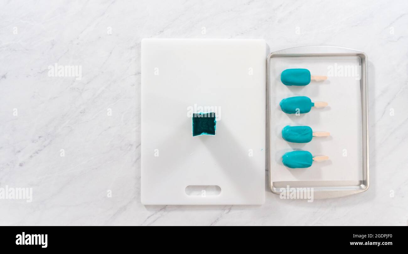 Flat lay. Dipping frozen cakesicles into melted chocolate to prepare ...