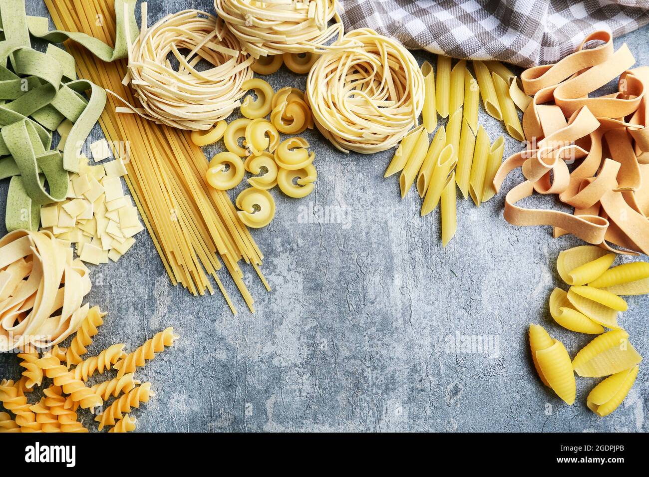 Mixed types and shapes of italian pasta on grey stone, background. Copy ...