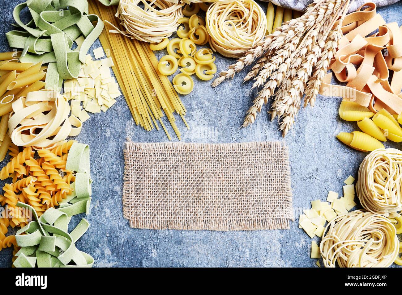 Mixed types and shapes of italian pasta on grey stone, background. Copy ...