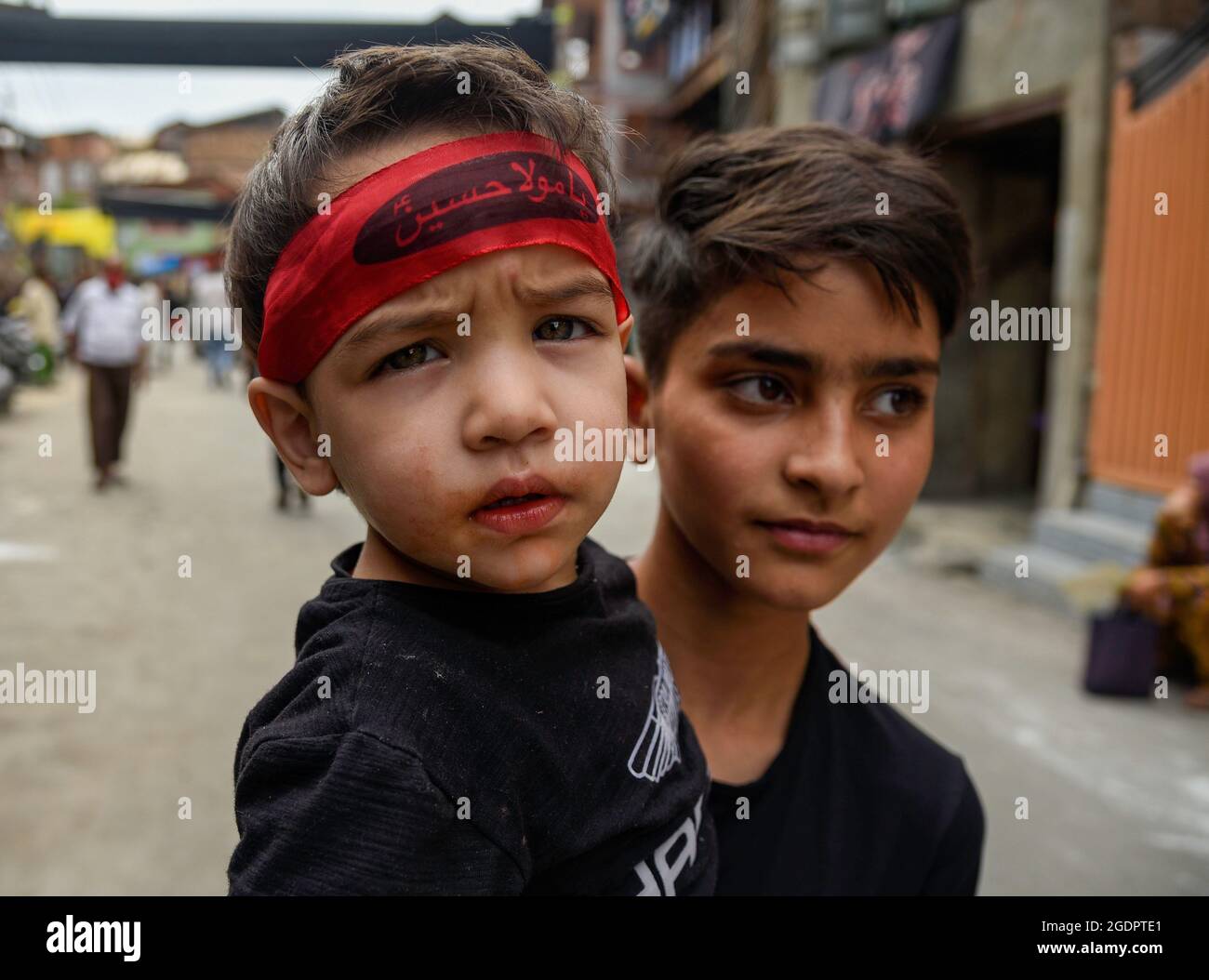 A Kashmiri boy carries a kid as they take part during a muharram ...