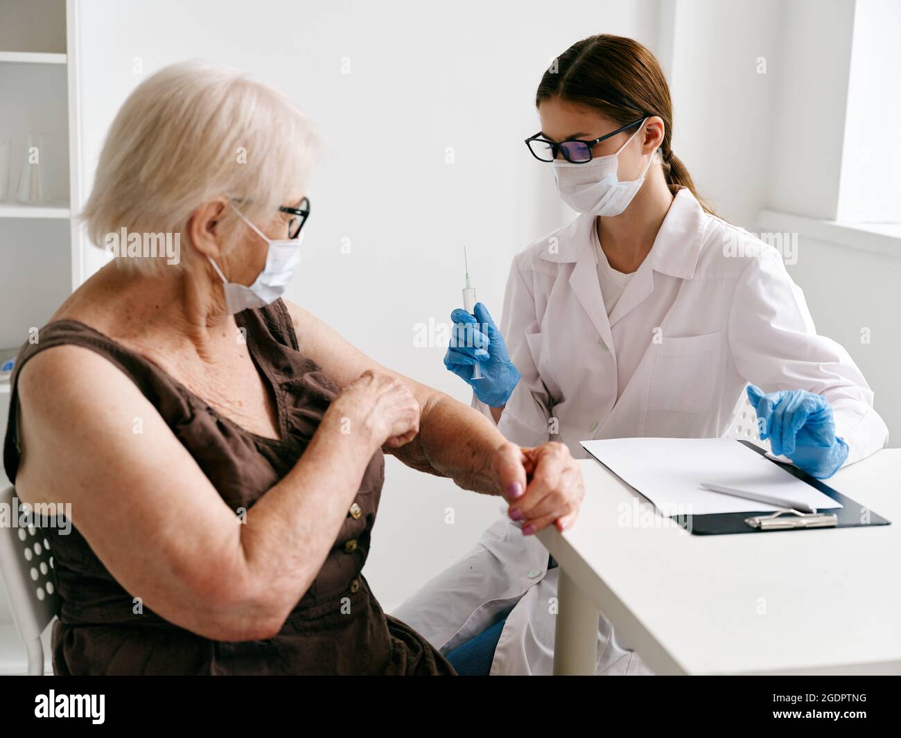 Nurse giving an injection to an elderly woman vaccine passport immunity ...