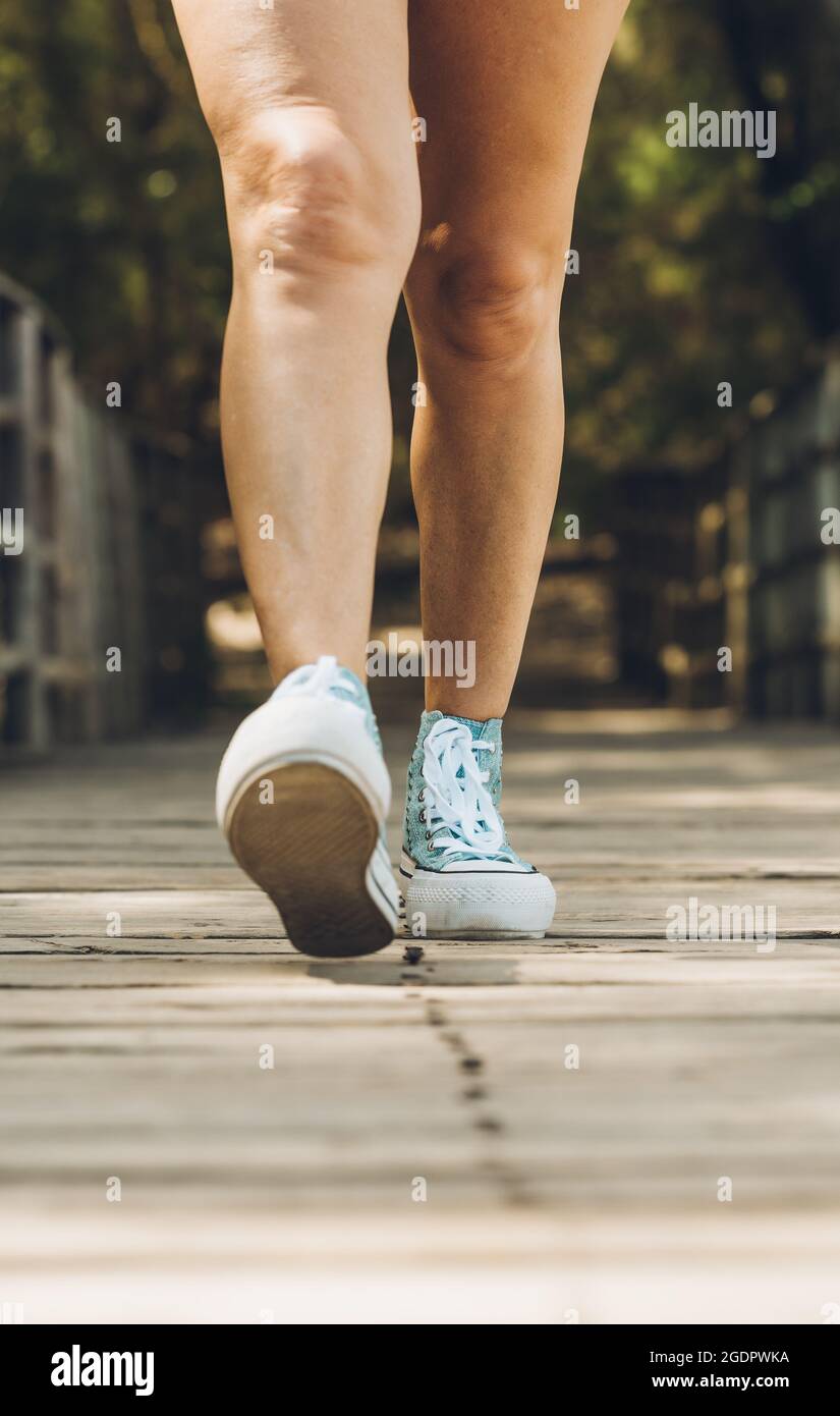 Legs of a woman walking across a wooden bridge Stock Photo - Alamy