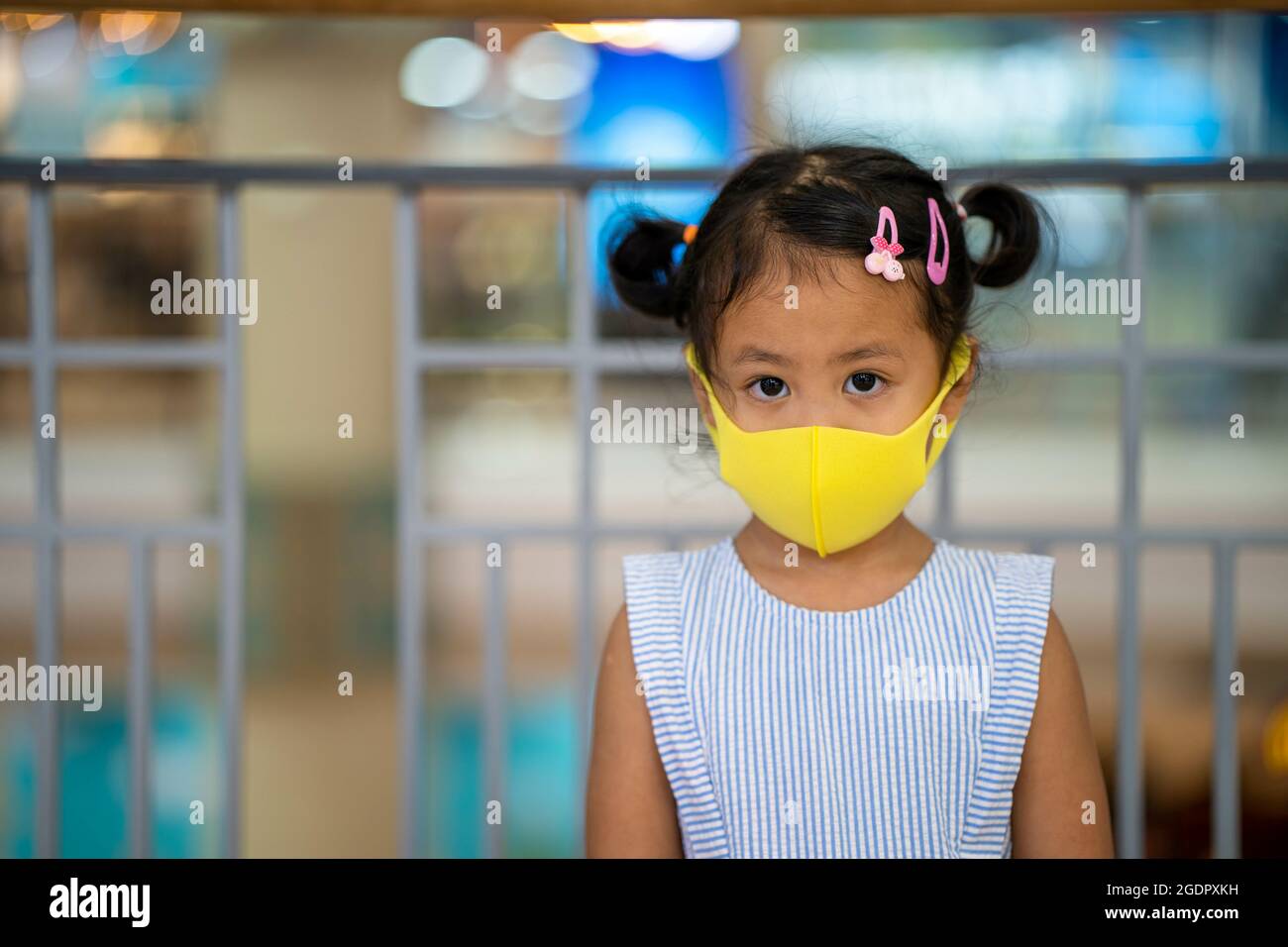 Cute Southeast Asian female child wearing a yellow protection face mask ...