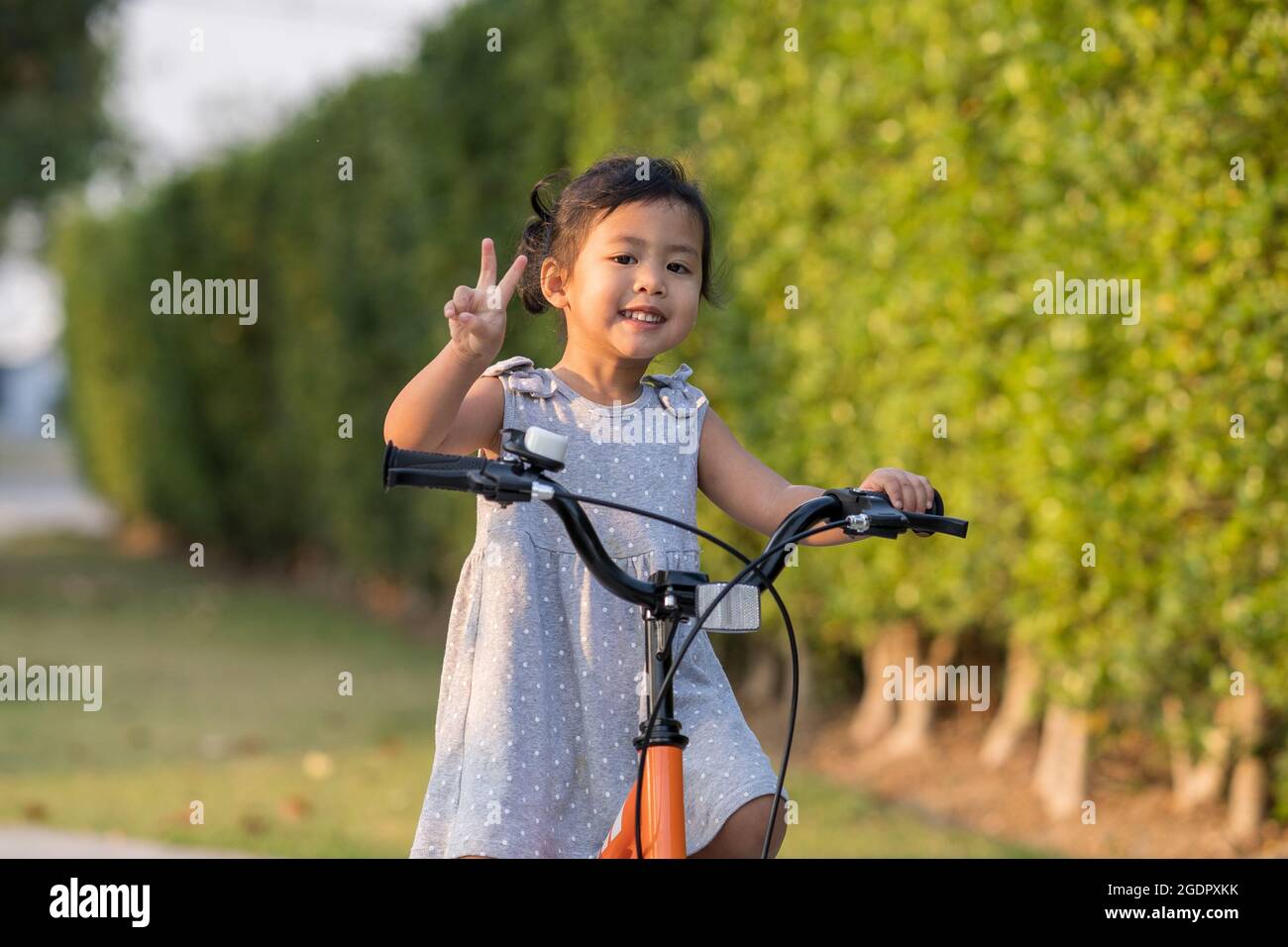 Cute Southeast Asian female child on her orange bike at a park Stock ...