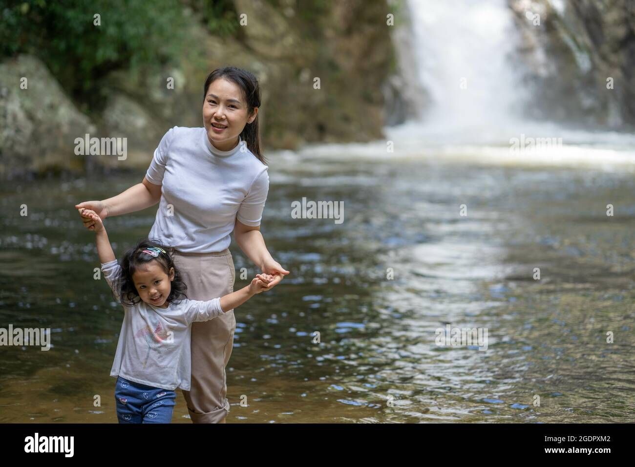 Southeast Asian mother and daughter standing in nature streams against ...