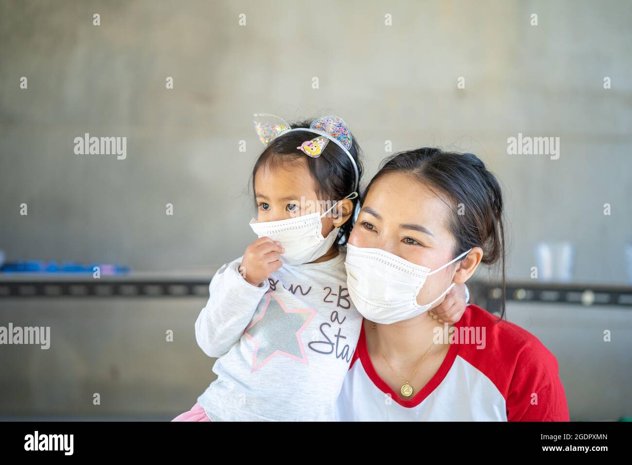 Southeast Asian mother and daughter wearing a facial mask for ...