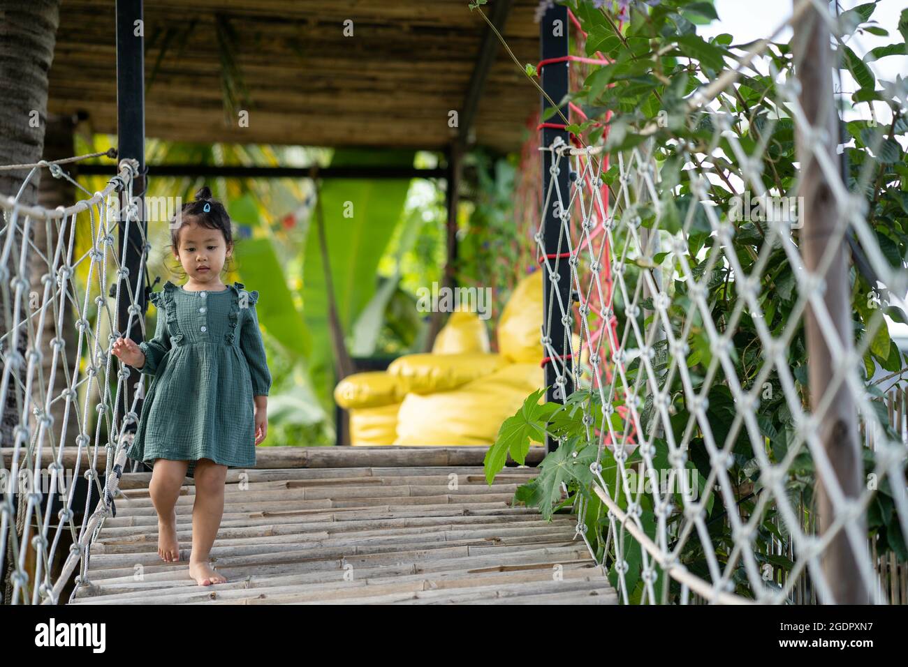 Cute Southeast Asian female child walking at the wooden bridge at a ...