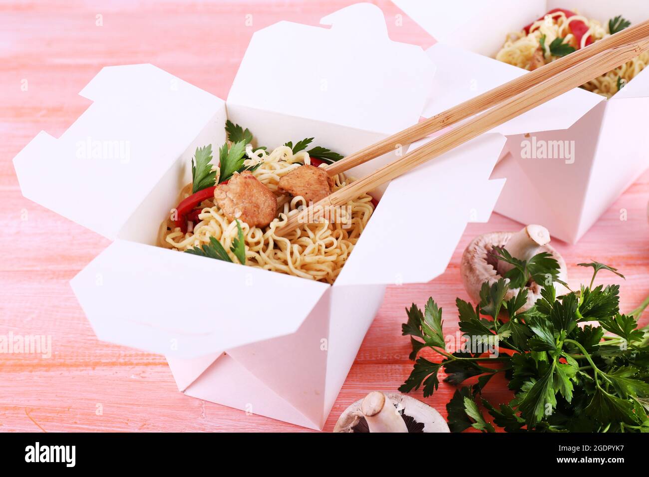 Chinese noodles with meat and pepper in takeaway boxes on pink ...