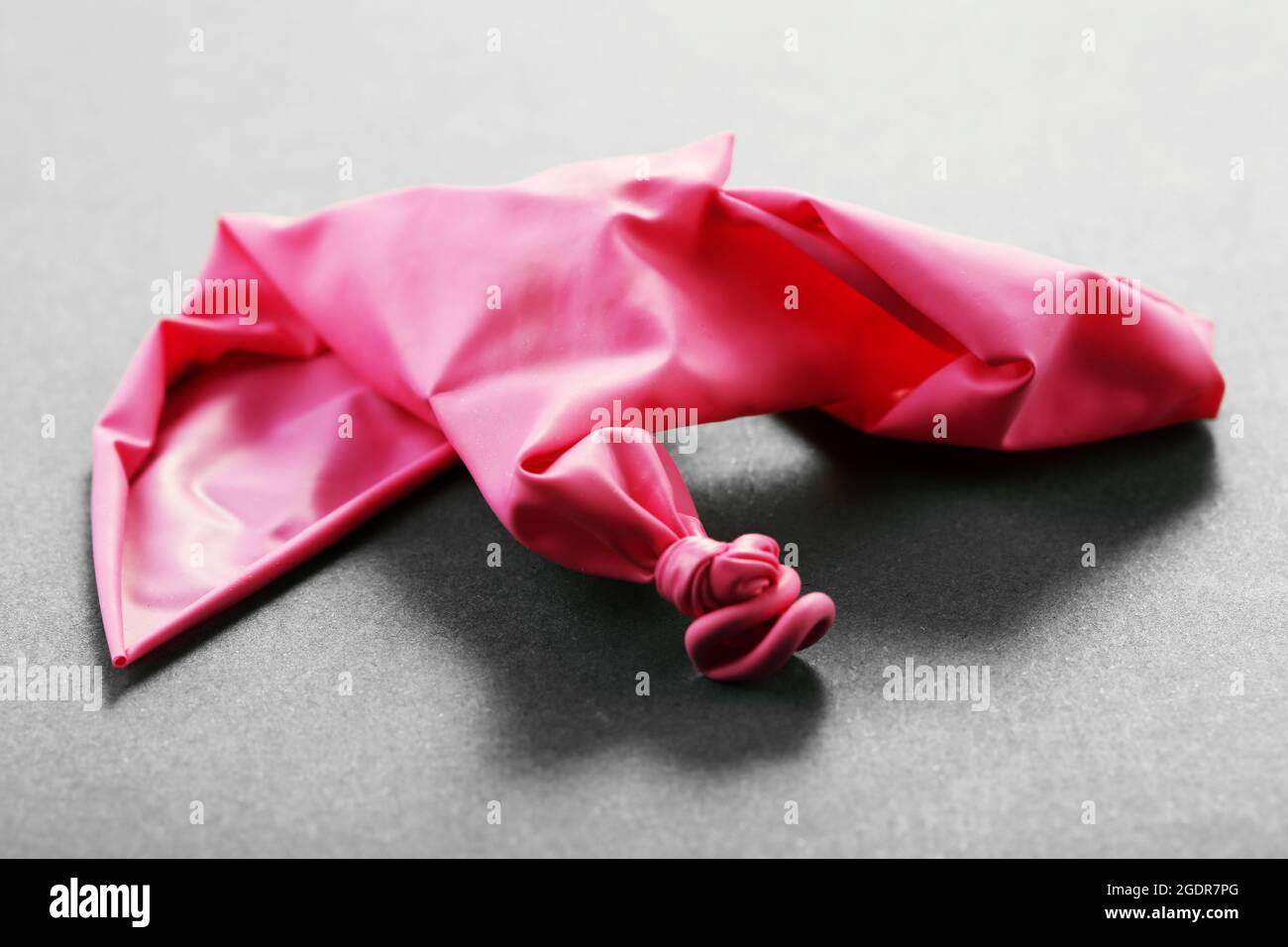 Popped pink balloon on paper background Stock Photo - Alamy