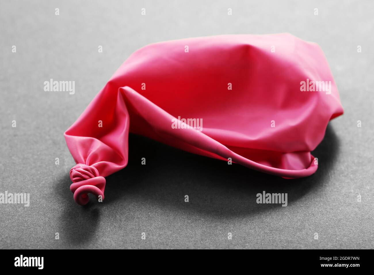 Popped pink balloon on paper background Stock Photo - Alamy