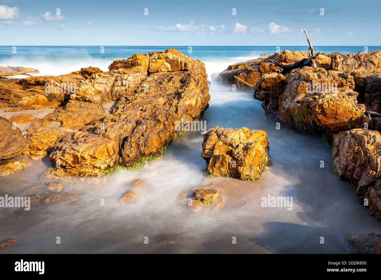 The tide sweeps through golden rocks on the Pacific Coast at ...