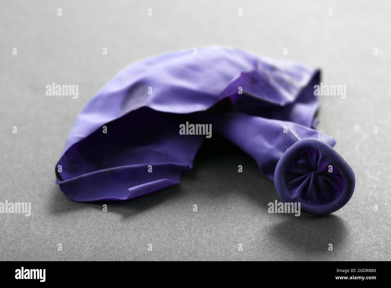 Popped violet balloon on paper background Stock Photo - Alamy