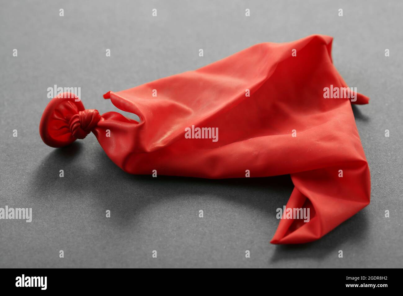 Popped red balloon on paper background Stock Photo - Alamy