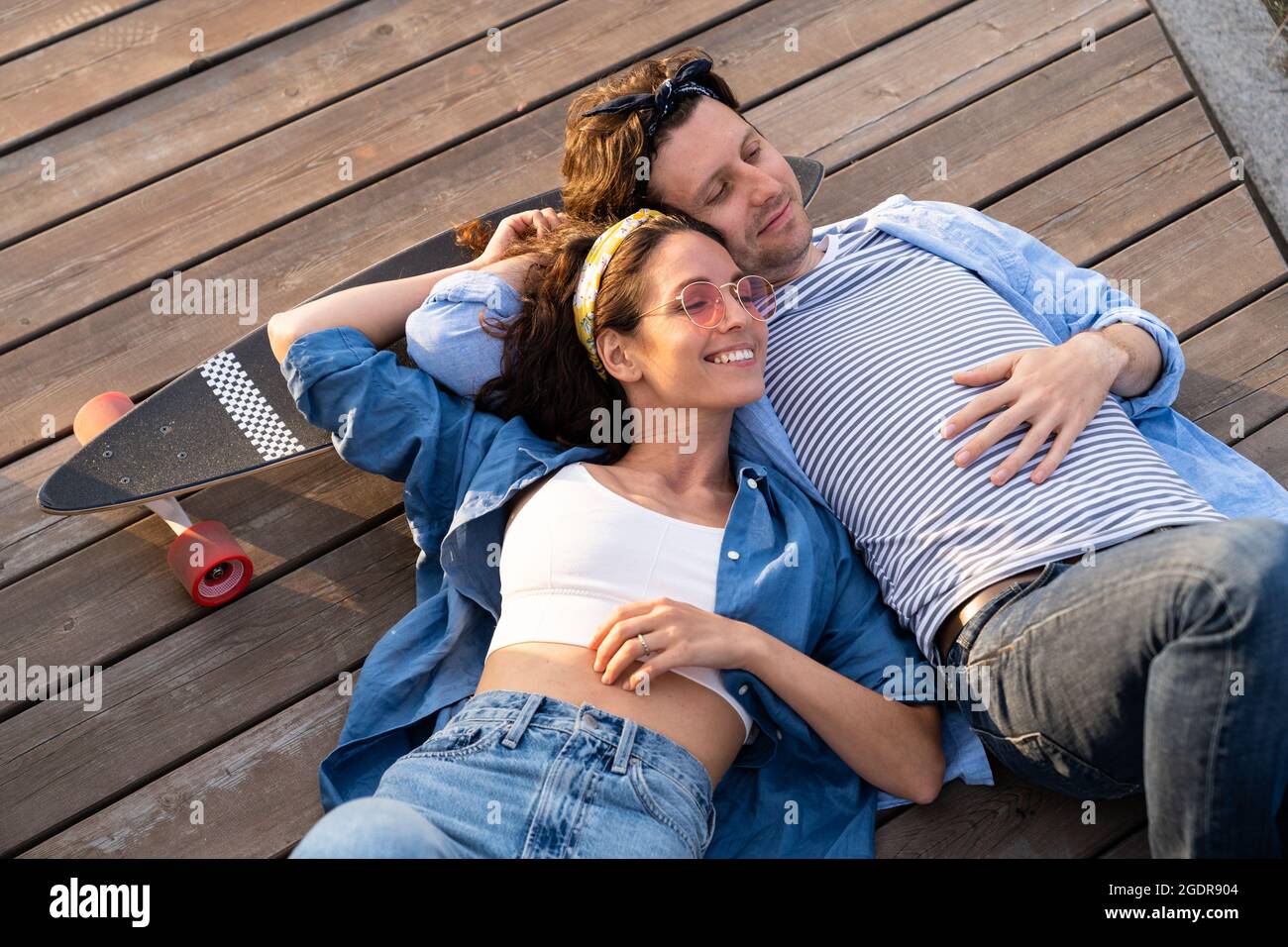Carefree young couple lying on skateboard cuddling enjoy sunset ...