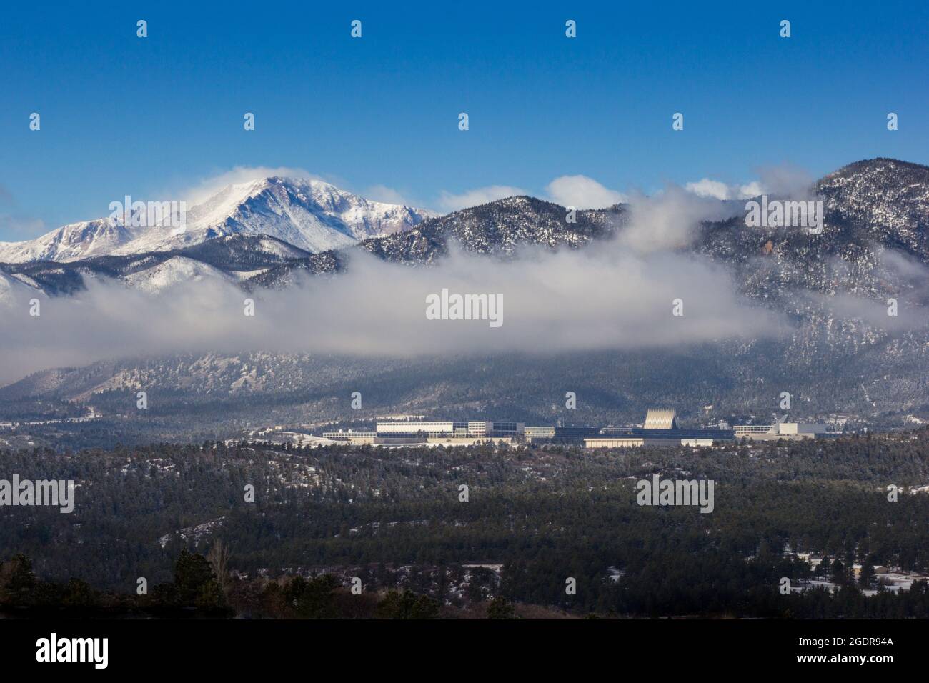 Morning clouds clear from over the US Air Force Academy under the shadow of a snowy Pikes Peak ...