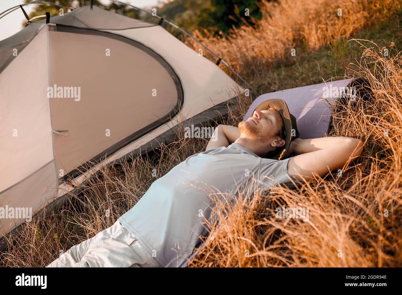 Sleeping man. A man laying on the grass near his tent and sleeping ...