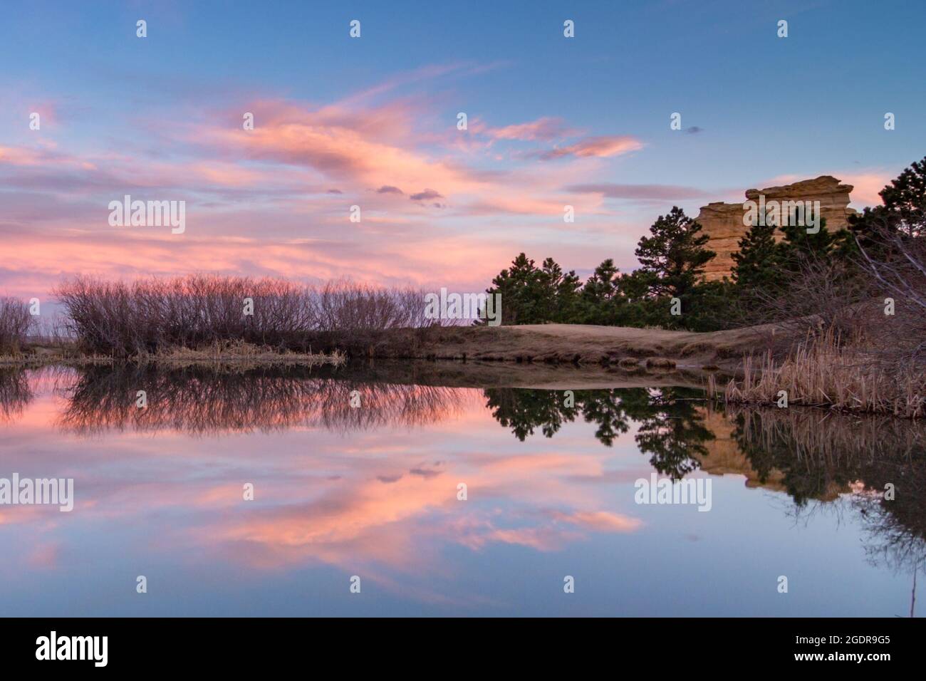 Glassy reflection of pink clouds and blue skies at sunset near Monument ...