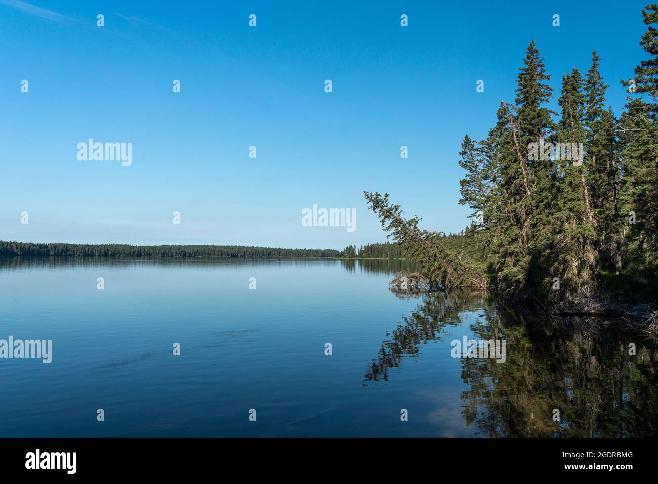 The shoreline of Clear Lake with reflections in Riding Mountain ...