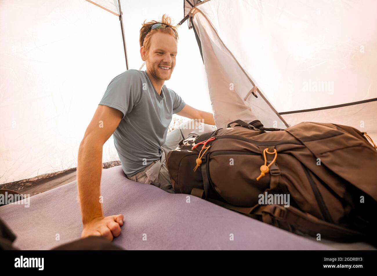 In a tent. A young man in a tent looking cheerful sitting near his ...