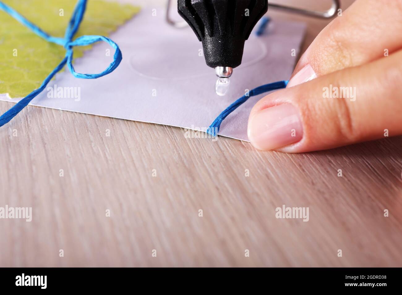 Woman's hand making postcard with blue ribbon and bow with a help of ...