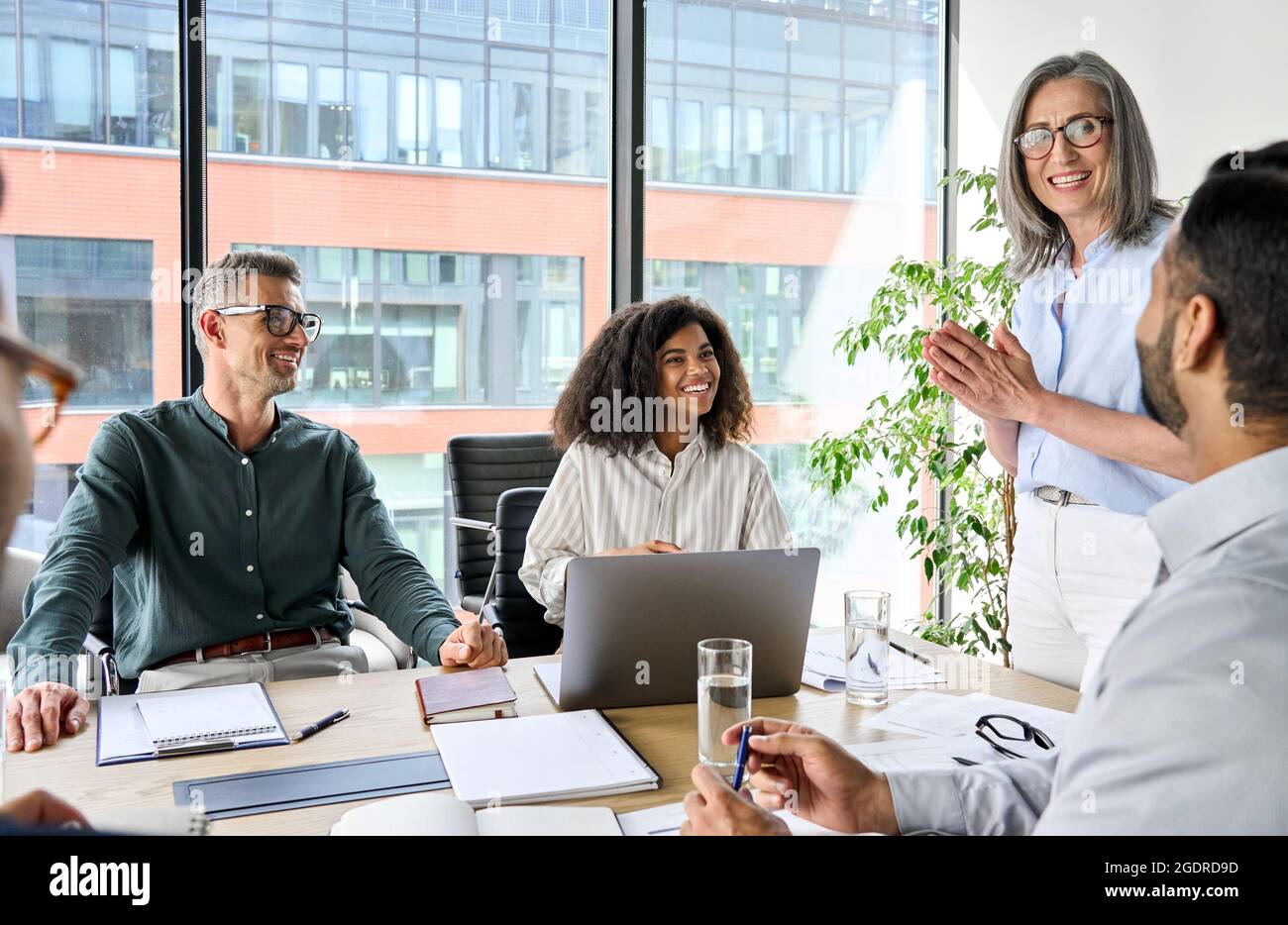 Happy diverse corporate team discussing project in boardroom office ...