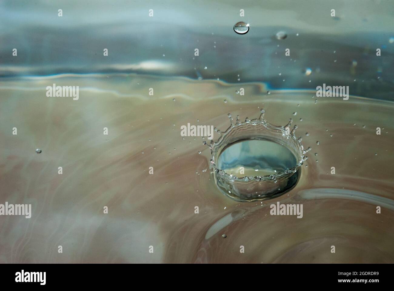 Closeup of a tiny water droplet splashing into the water with a blurry ...