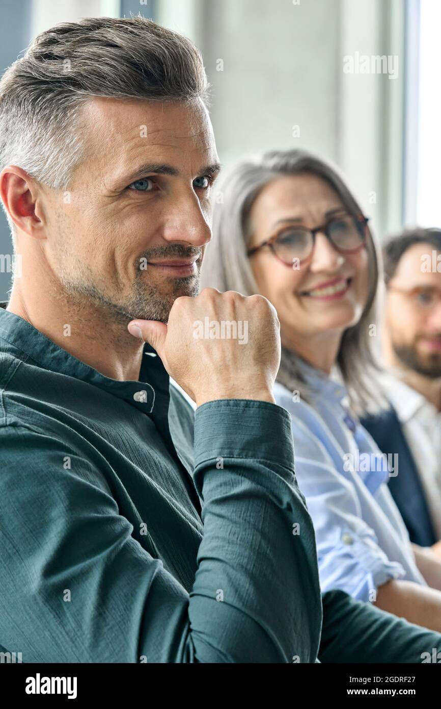 Smiling mature businessman sitting at office desk with executive team ... Smiling mature businessman sitting at office desk with executive team ...