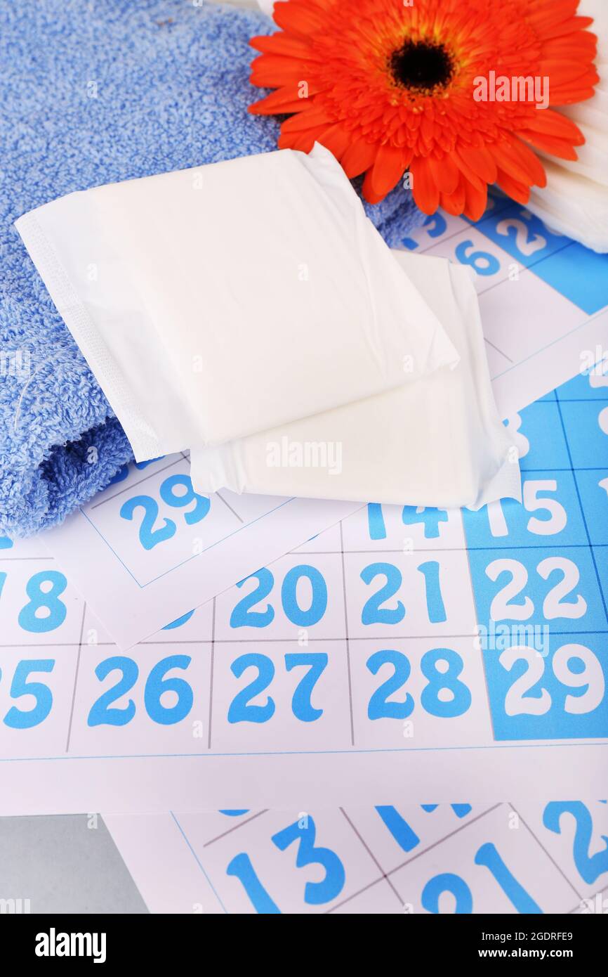 Sanitary pads, orange Gerber and towel on blue calendar background ...