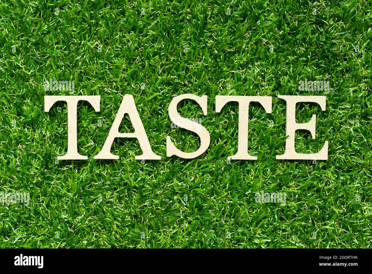 Wood letter in word taste on green grass background Stock Photo - Alamy