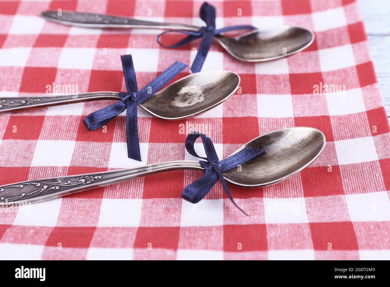 Metal spoons on checkered fabric background Stock Photo - Alamy