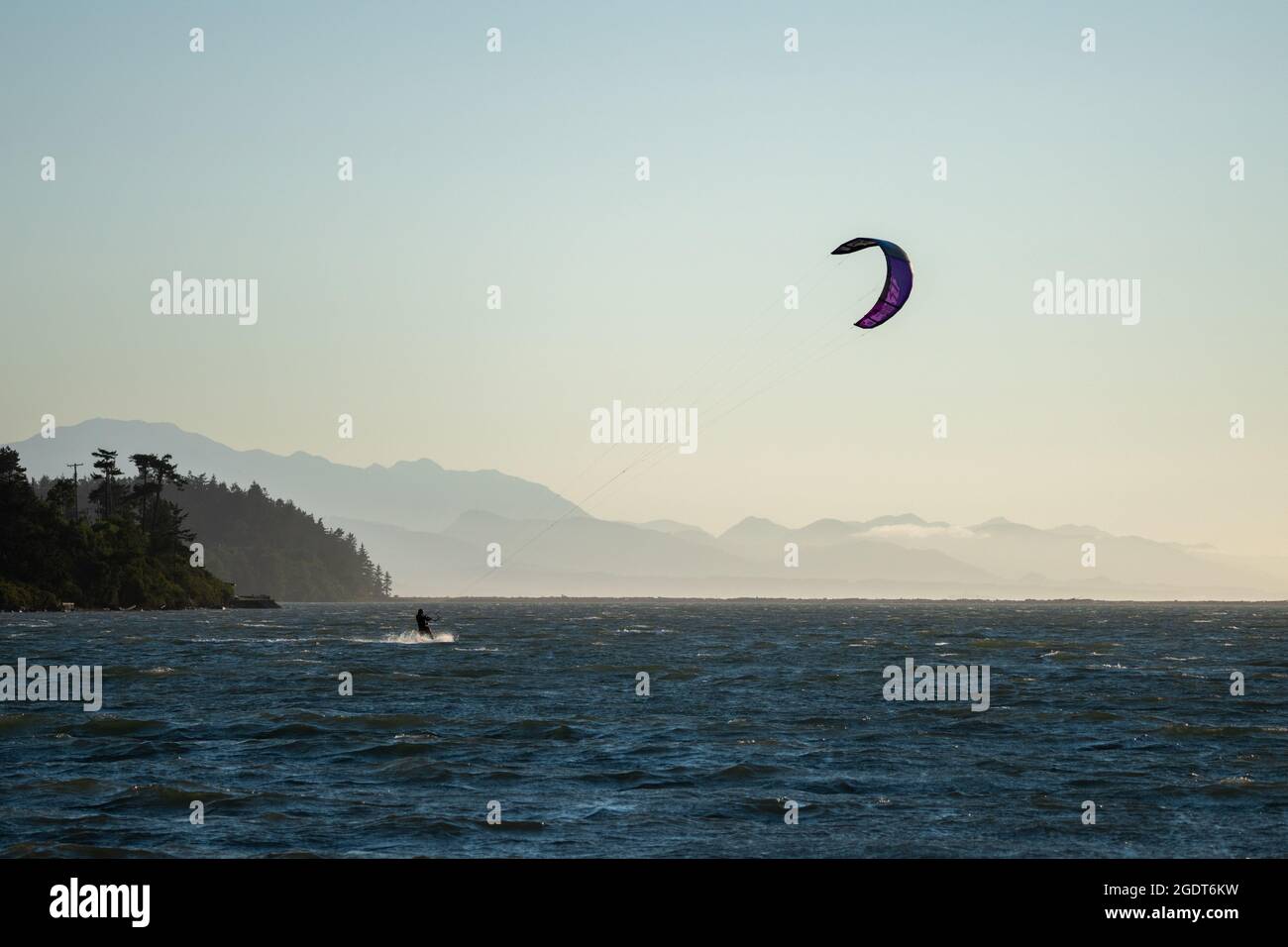 sunset kite surfing in the sea with mountains in the background Stock ...