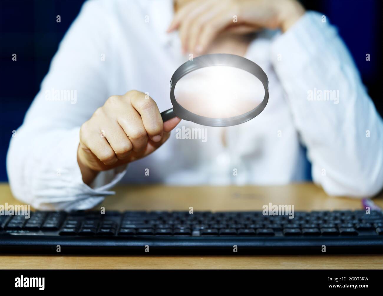 Businessman examining computer equipment with glowing magnifying glass ...