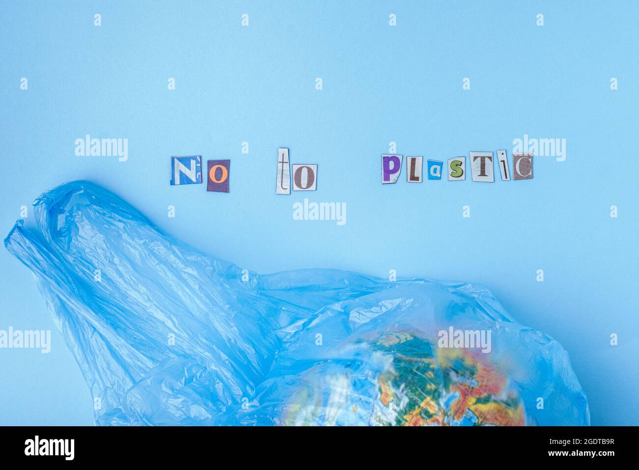 no to plastic words cut out of magazine. Flat lay, on a blue background ...