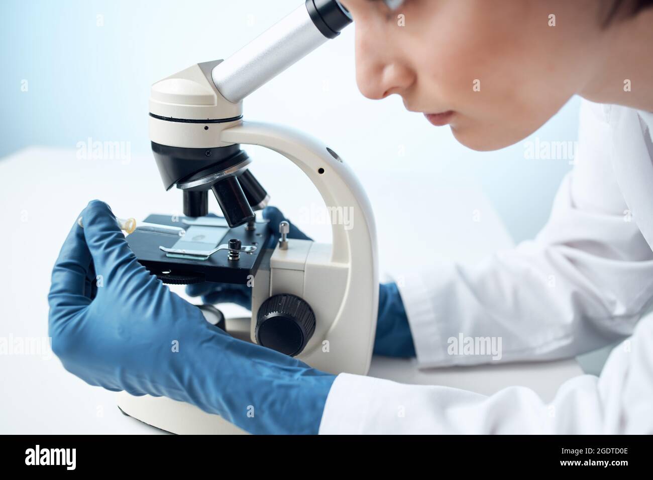 woman looking through a microscope diagnostics science research close ...
