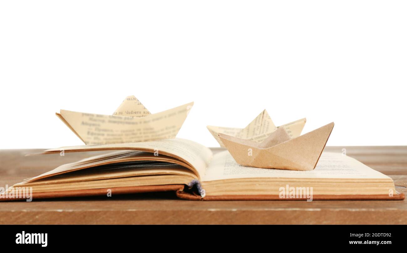 Origami boats on old book on wooden table, on white background Stock ...