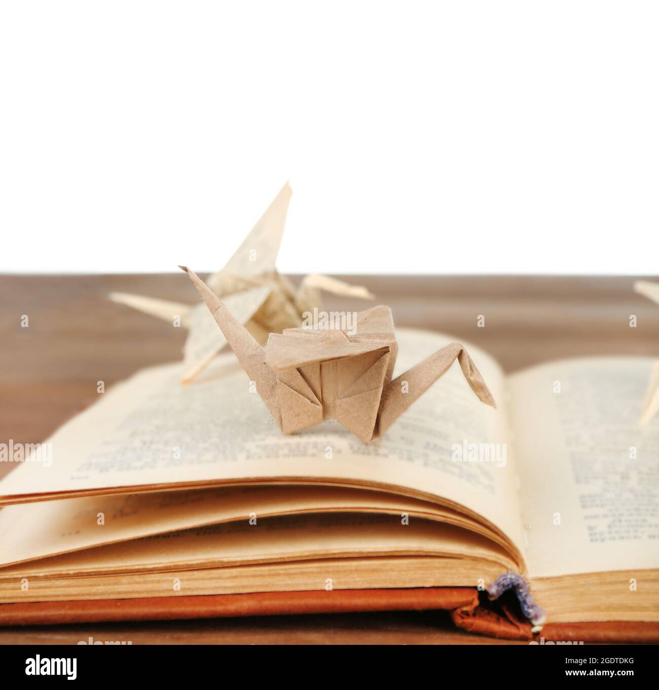 Origami cranes on old book on wooden table, on white background Stock ...